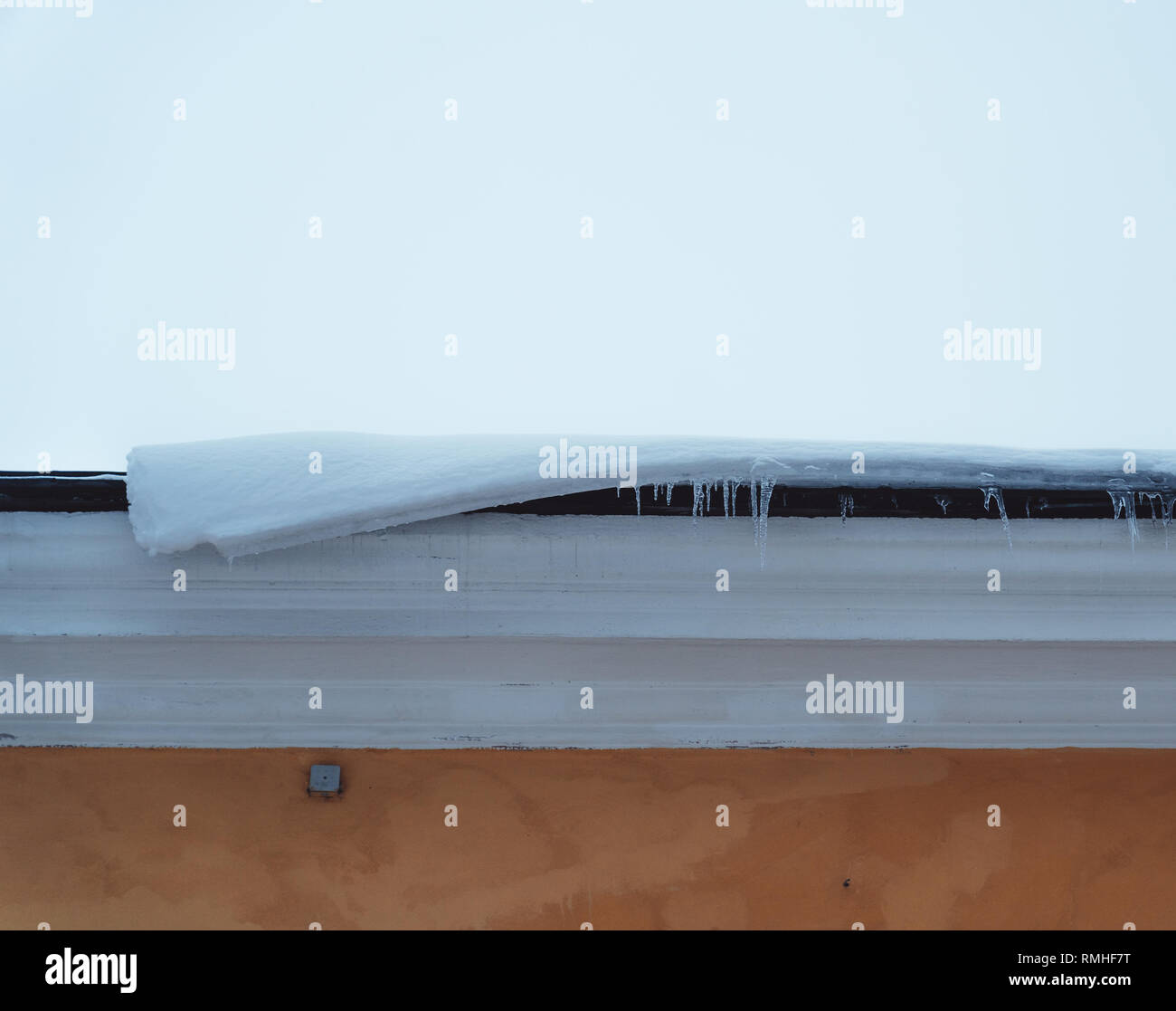 Snow starting to melt on the roof of a building and hanging over the ...