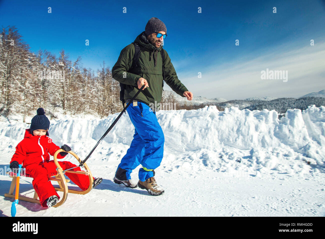 Happy father and his son enjoying sledding ride. Happy family with sled ...