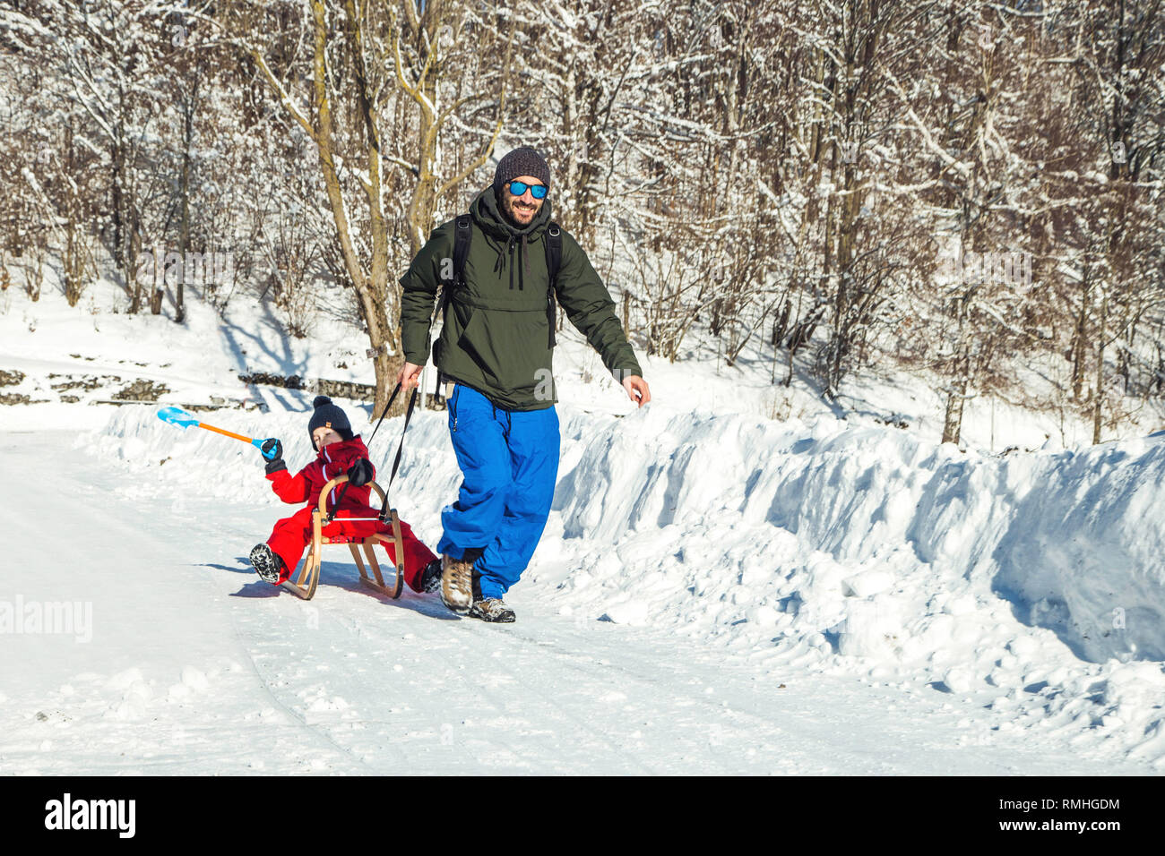 Happy father and his son enjoying sledding ride. Happy family with sled ...