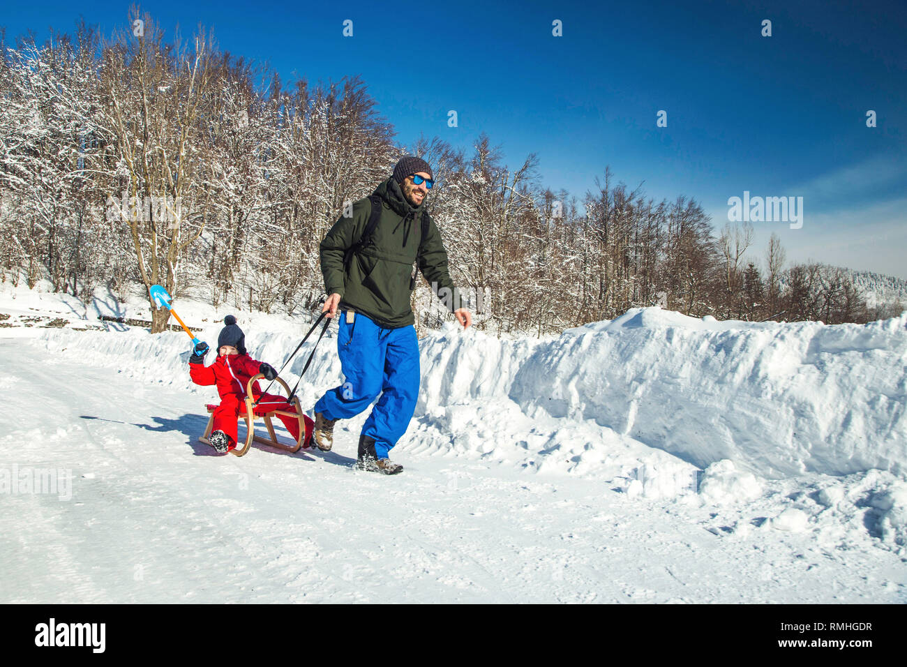 Happy father and his son enjoying sledding ride. Happy family with sled ...