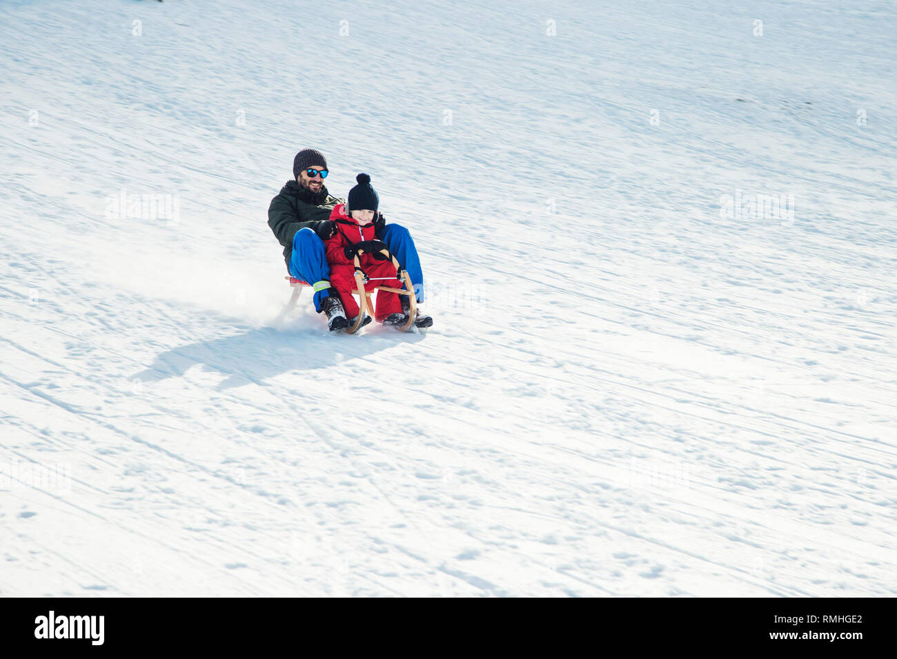 Happy father and his son enjoying sledding ride. Happy family with sled ...