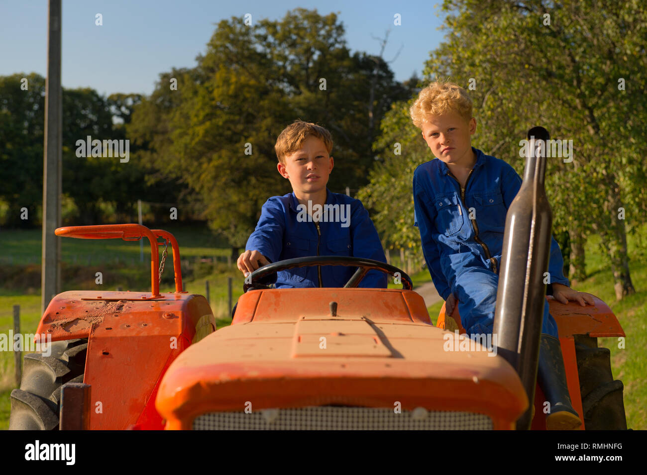 Farm boys riding on orange tractor Stock Photo - Alamy
