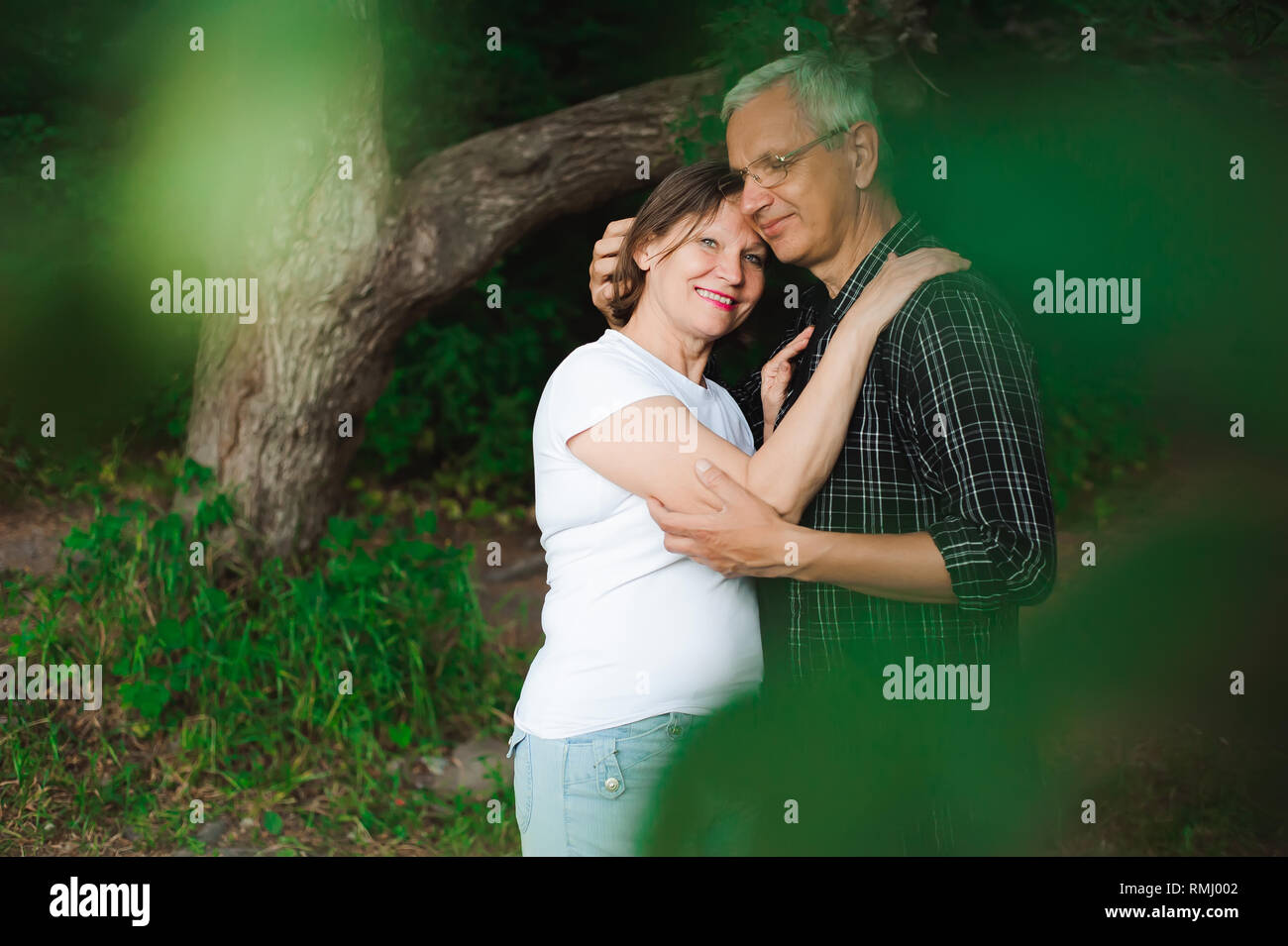 Active Loving Senior Couple Walking In Beautiful Summer Forest Stock