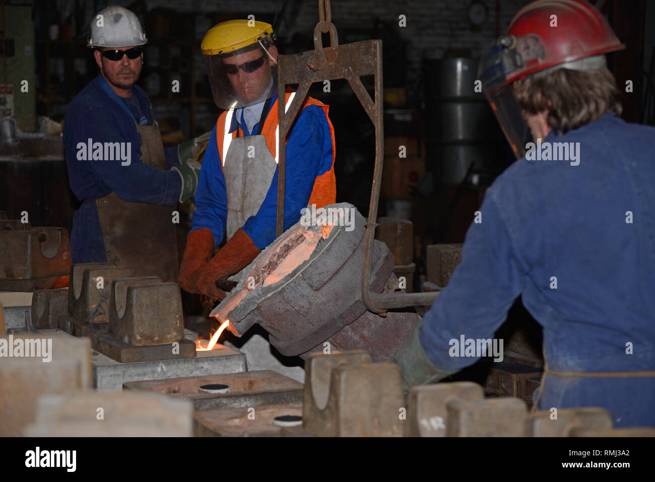 Foundrymen pour molten iron into moulds for making fire grates Stock ...