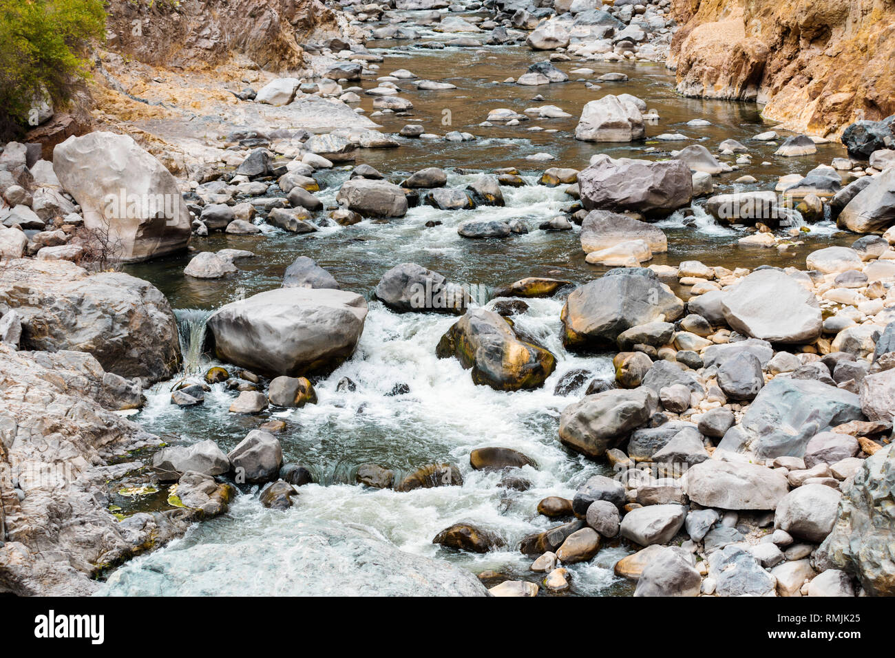 famous Colca river flowing in canyon covered by big stones in Peru ...