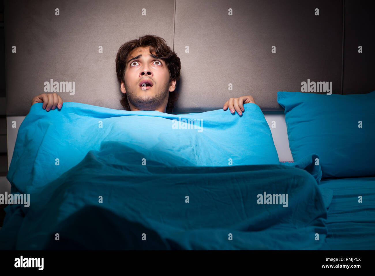 Young man scared in his bed having nightmares Stock Photo - Alamy