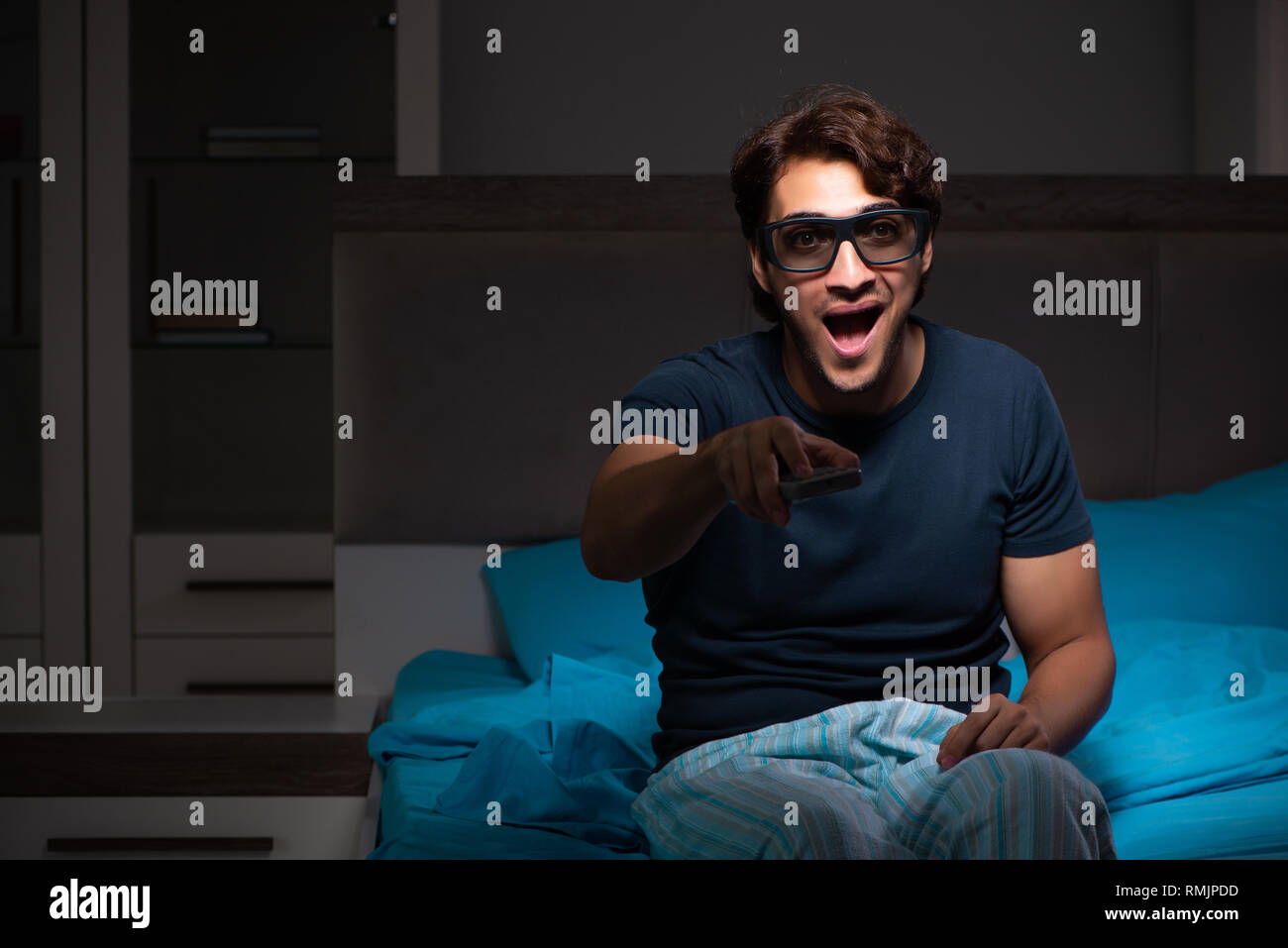 Man watching tv at night in bed Stock Photo - Alamy