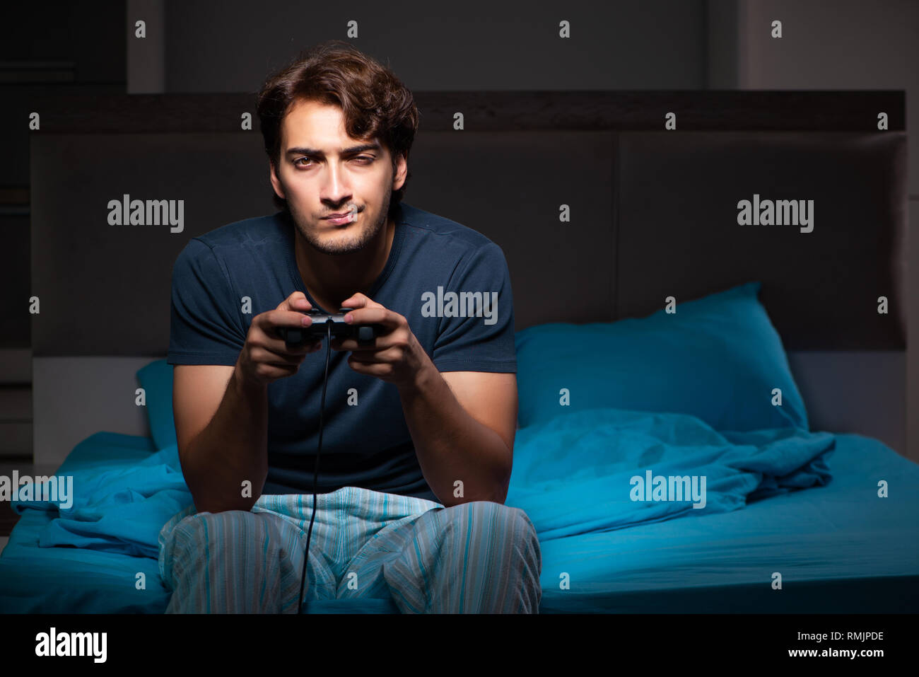 Young man playing computer games at night in bed Stock Photo - Alamy