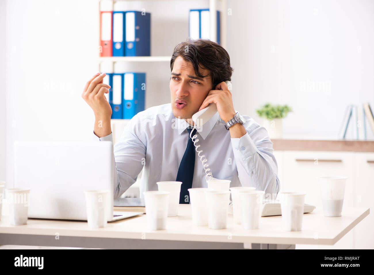 Young employee addicted to coffee Stock Photo - Alamy