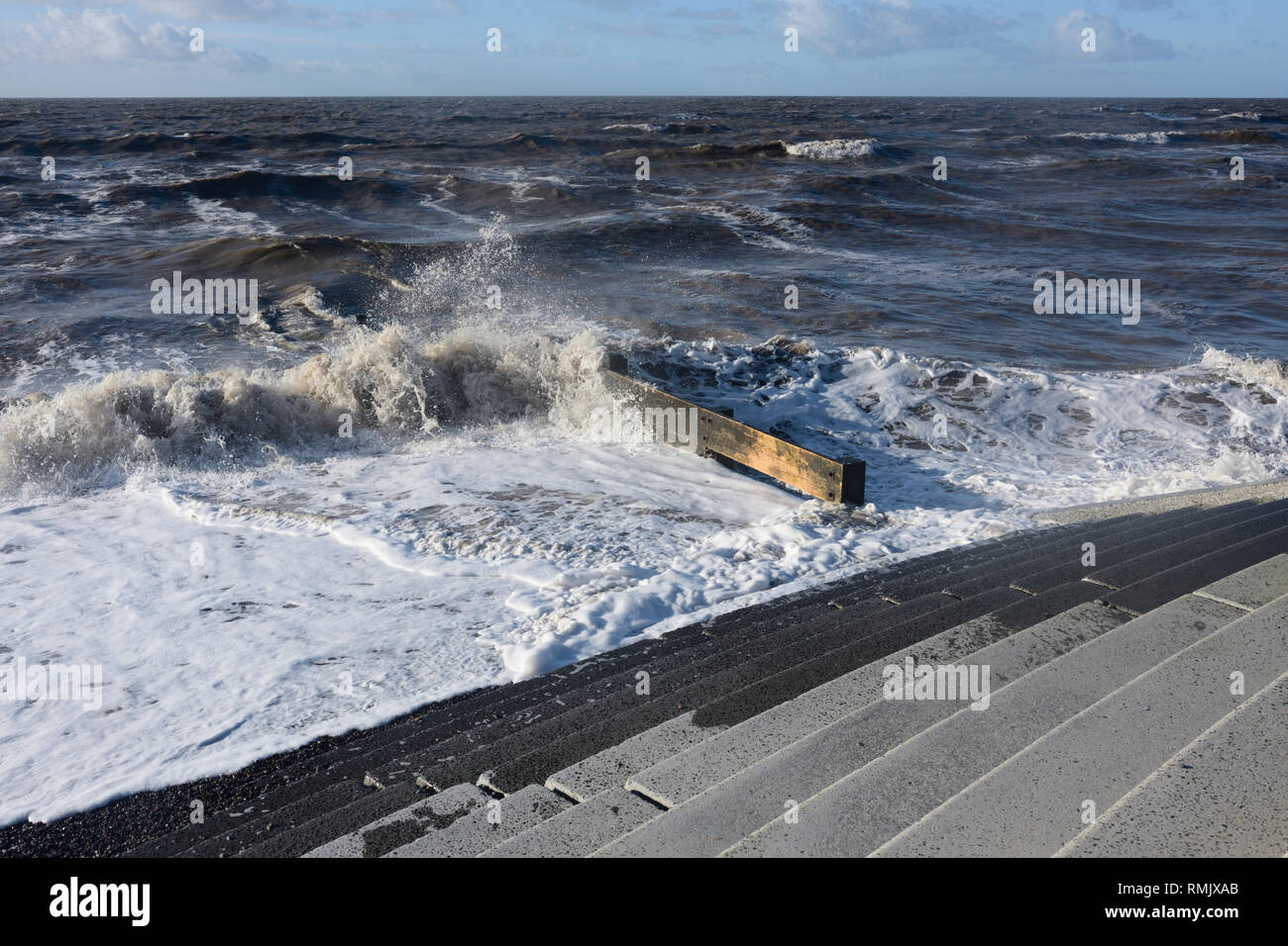 Waves from rough sea breaking on timber groyne and concrete stepped ...
