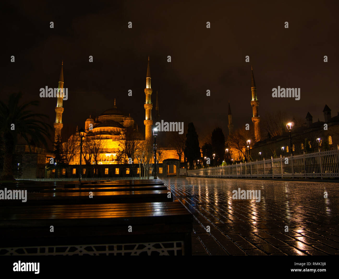 An illuminated mosque at night with reflections from the rain on the ...