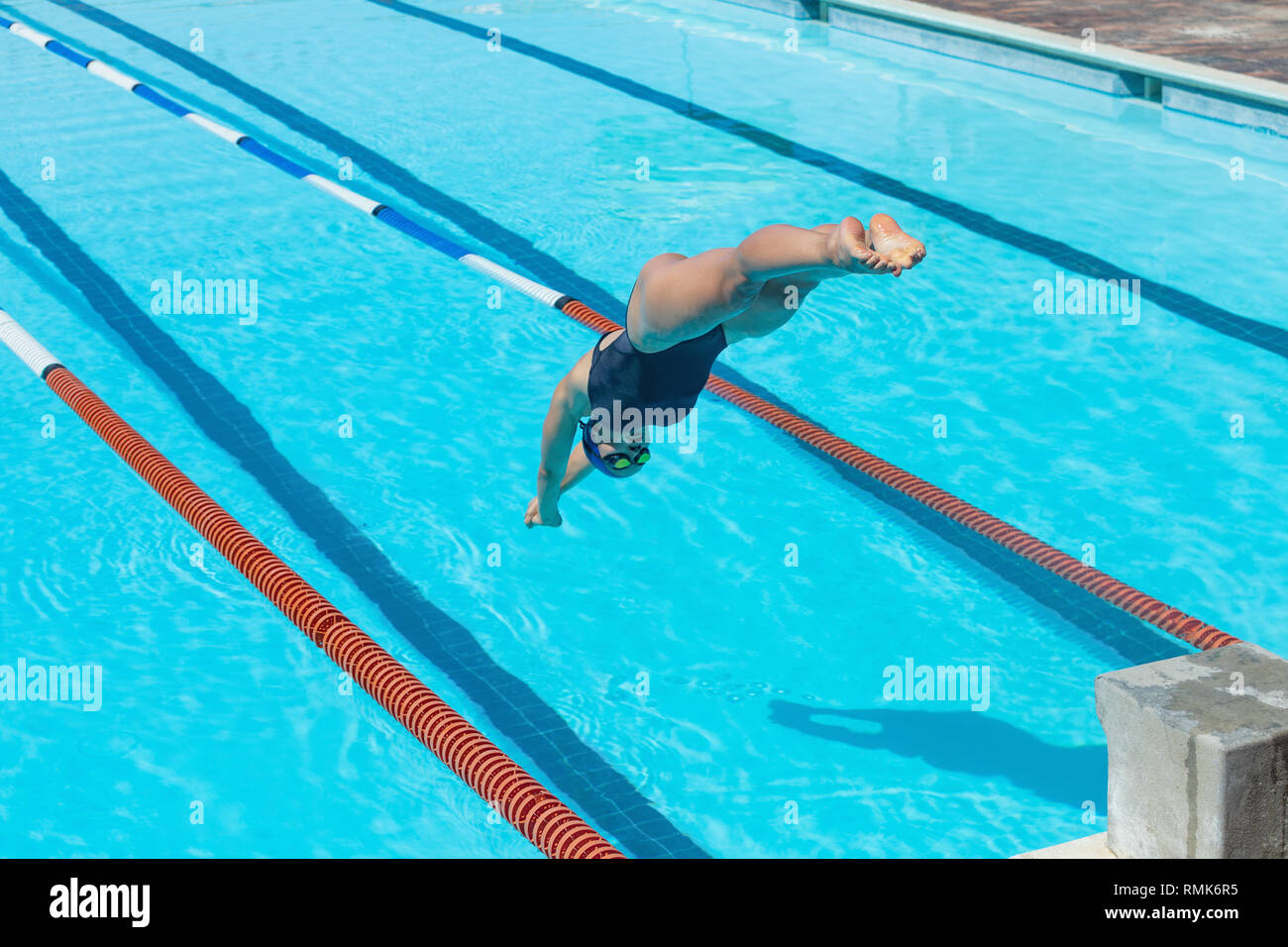 Young Caucasian female swimmer jumping into water of a swimming pool ...