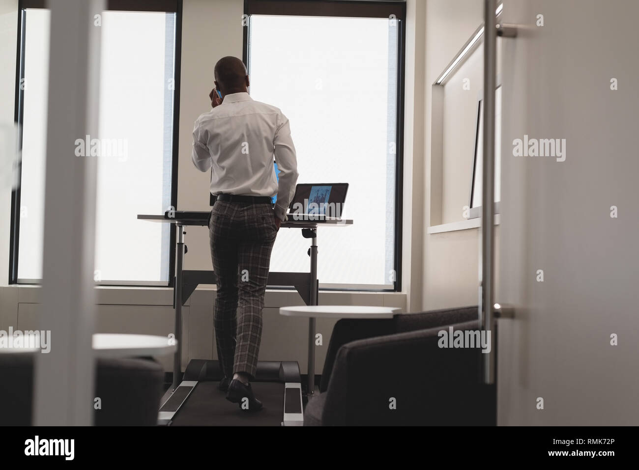 Man using his mobile phone while exercising on treadmill Stock Photo ...