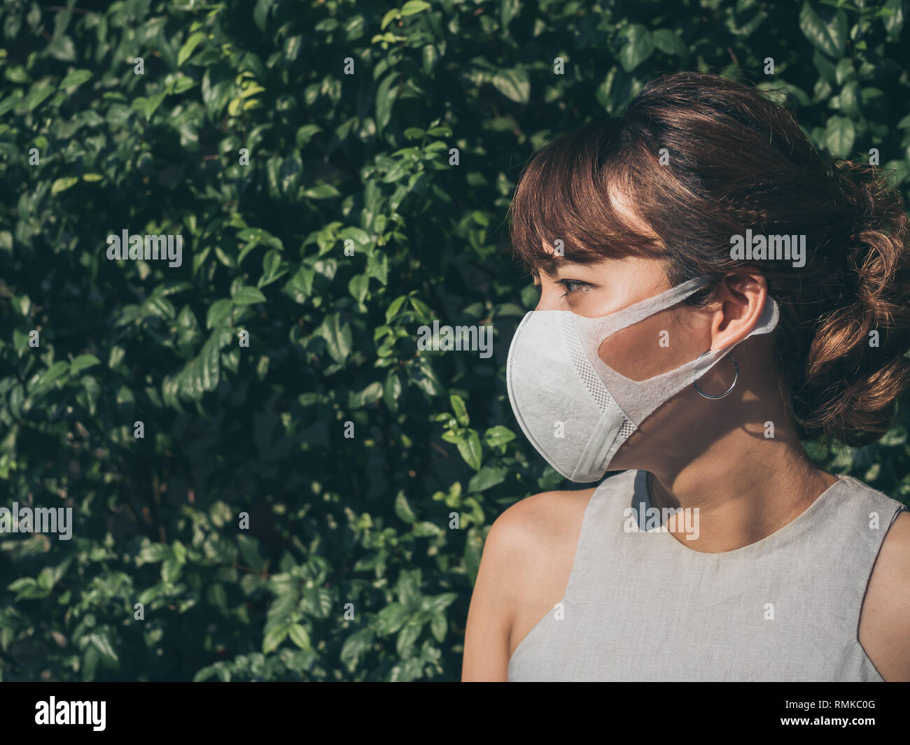 Beautiful asian woman wearing white protective N95 dust mask on green ...
