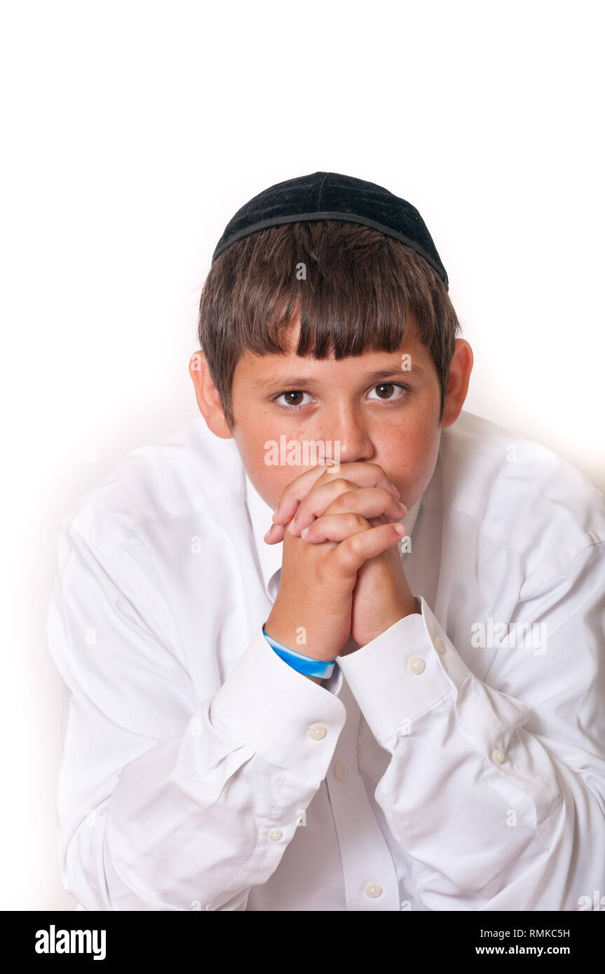 Jewish boy looks towards the camera while praying. Isolated on white ...