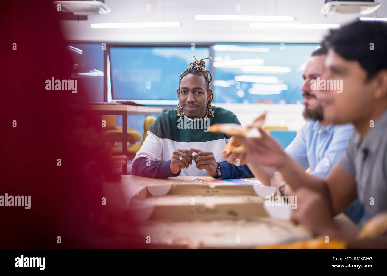 Friendly diverse multiethnic business team eating sharing pizza together in startup office ...