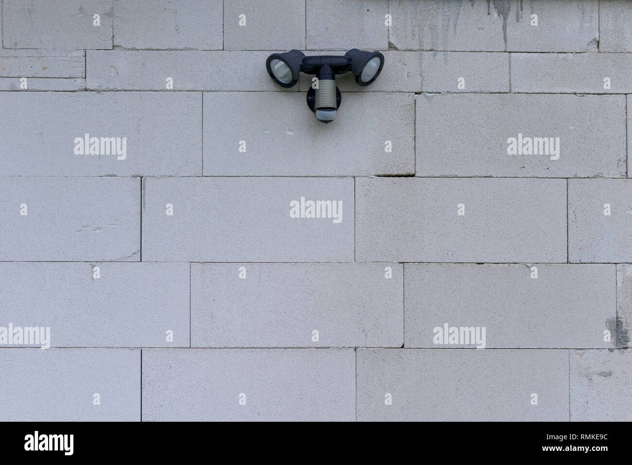 Two external security lights with motion sensor mounted on a cement ...
