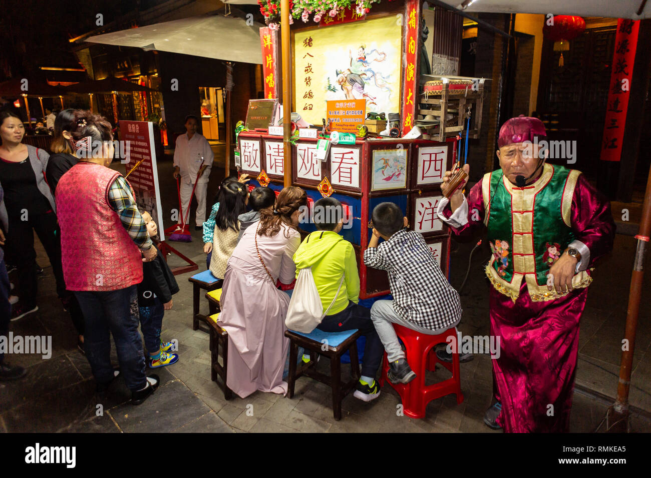 Chinese spectators watch a Peking peep show at a park in Shenzhen ...