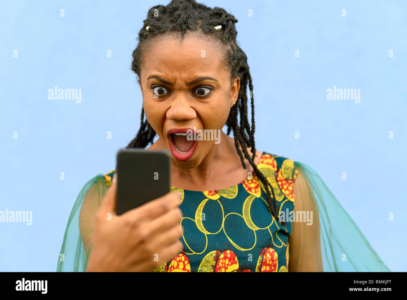 Horrified upset young African American woman in a stylish dress gawping ...