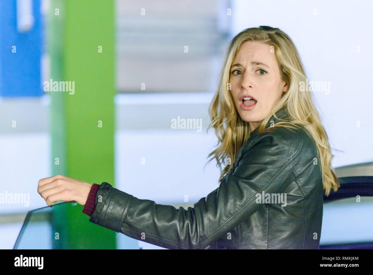 Startled young woman looking behind her with her mouth agape as she ...