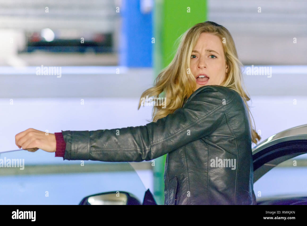 Startled young woman looking behind her with her mouth agape as she ...