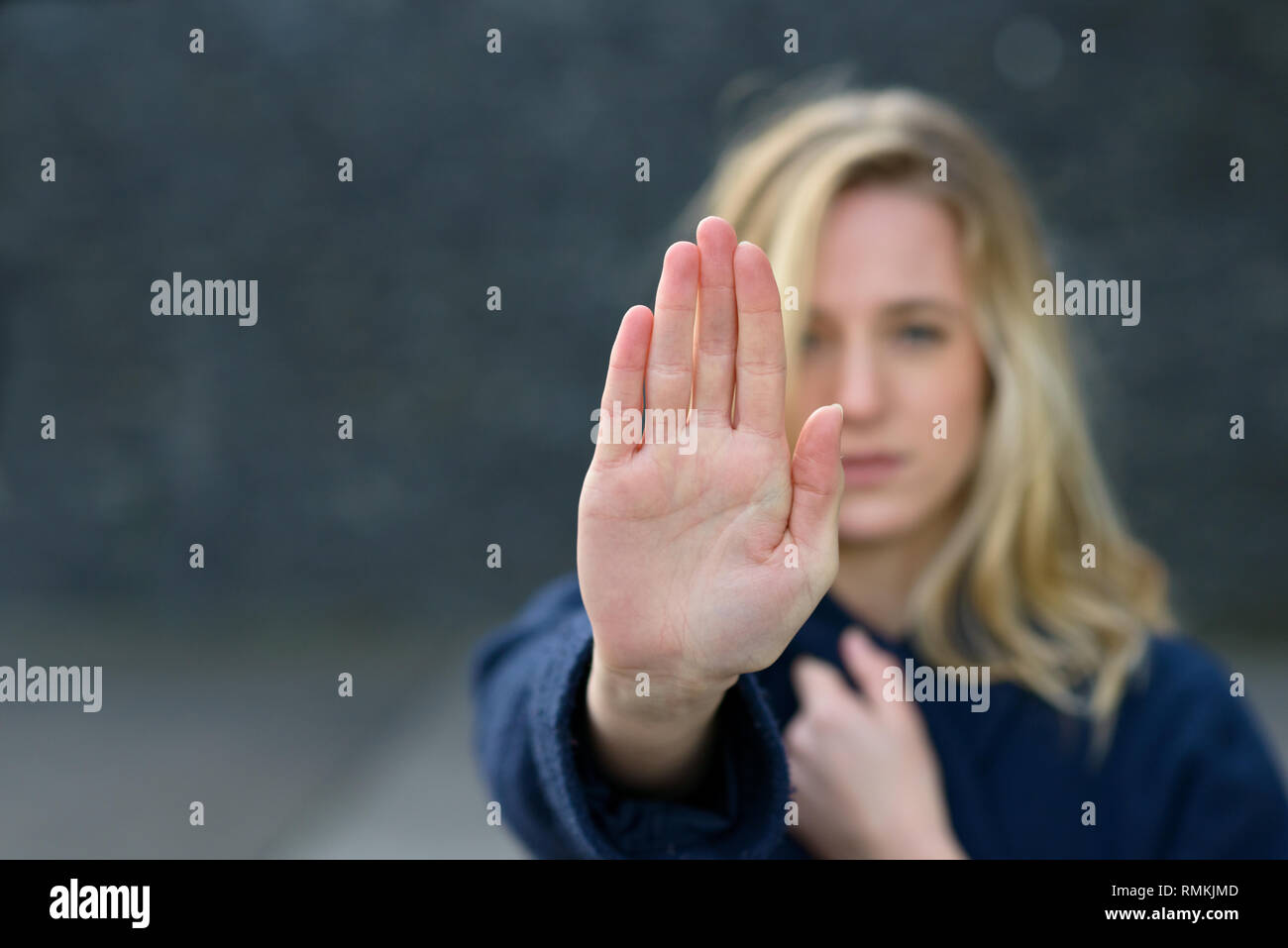 Young woman making a halt or stop gesture with the raised palm of her ...
