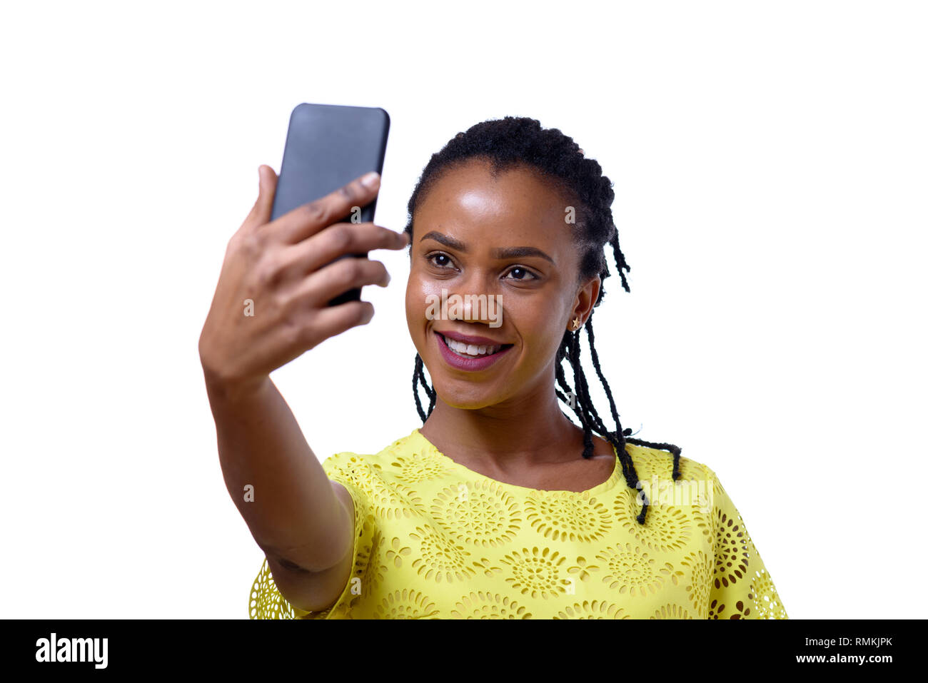 Cheerful dark-skinned woman taking selfie with smartphone against white ...
