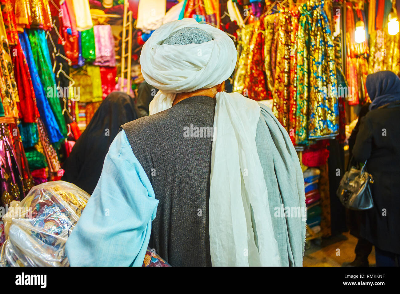 The elderly Iranian in white turban stands at the textile shop with ...