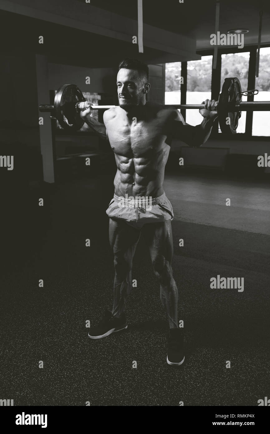 Strong Man In The Gym Exercising Legs With Barbell - Muscular Athletic ...