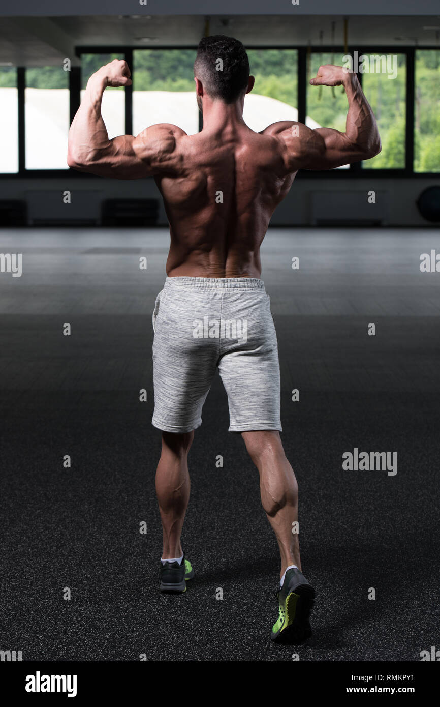 Young Man Standing Strong In The Gym And Flexing Muscles - Muscular ...