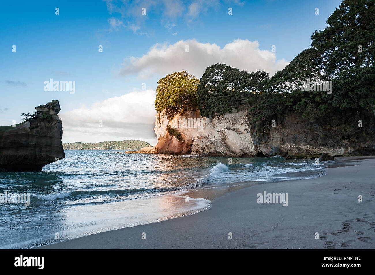 Sun shines on a rocky promontory, in Cathedral Cove, New Zealand ...