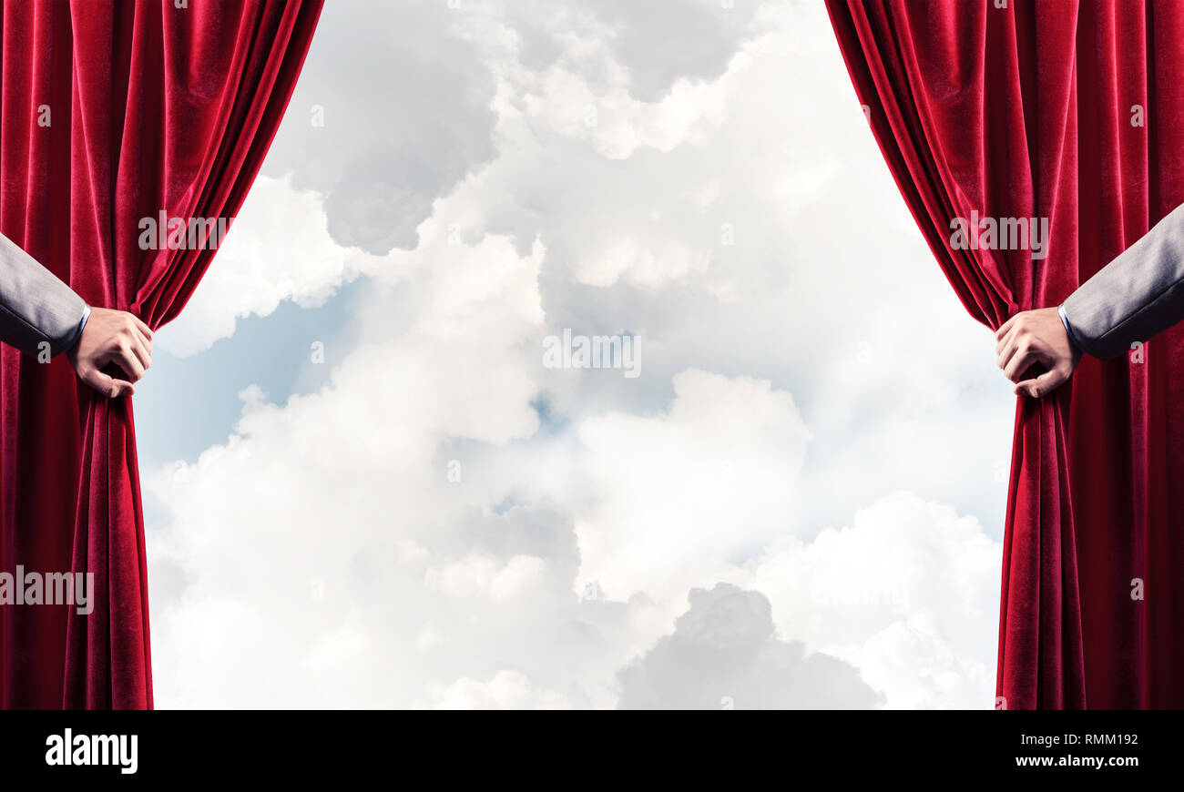 Cloudy landscape behind red curtain and hand holding it Stock Photo - Alamy