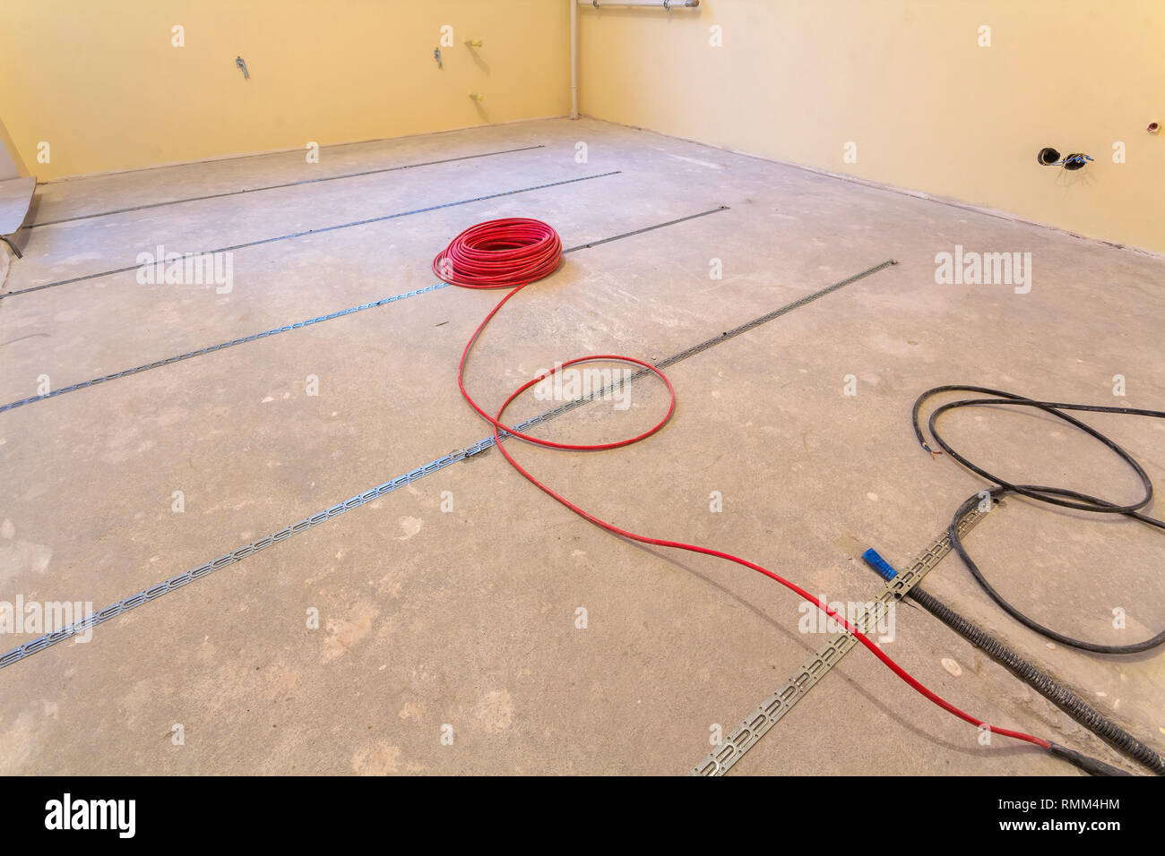 Heating red electrical cable wire installation on cement floor in small ...
