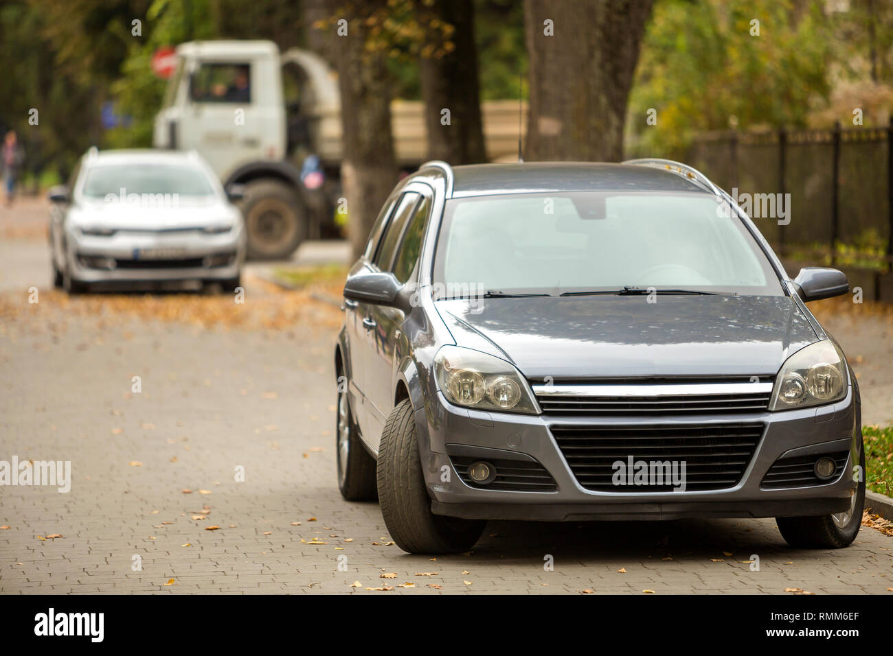 Gray shiny car parked in quiet area on asphalt road on blurred bokeh ...