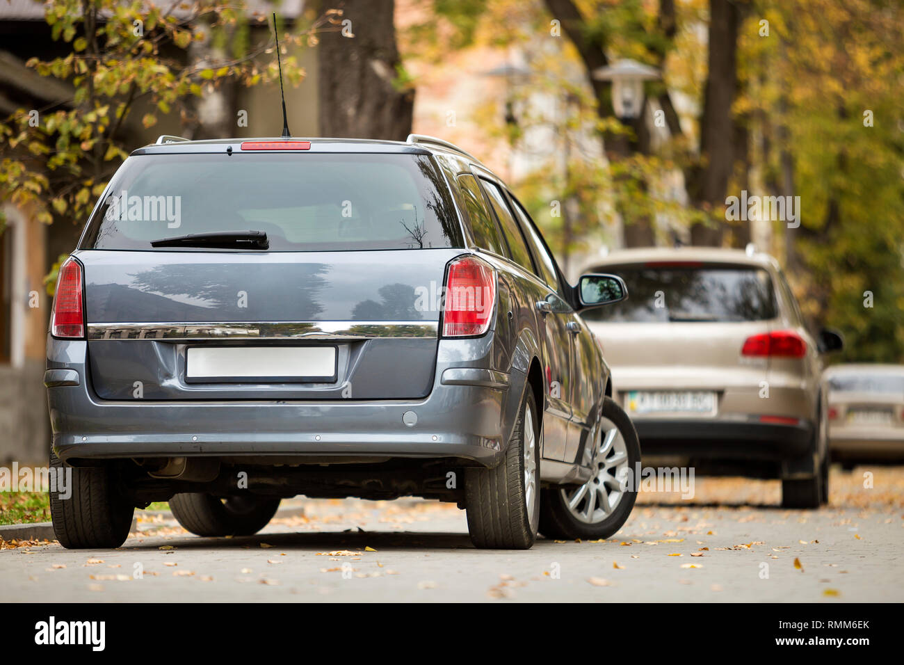 Gray shiny car parked in quiet area on asphalt road on blurred bokeh ...