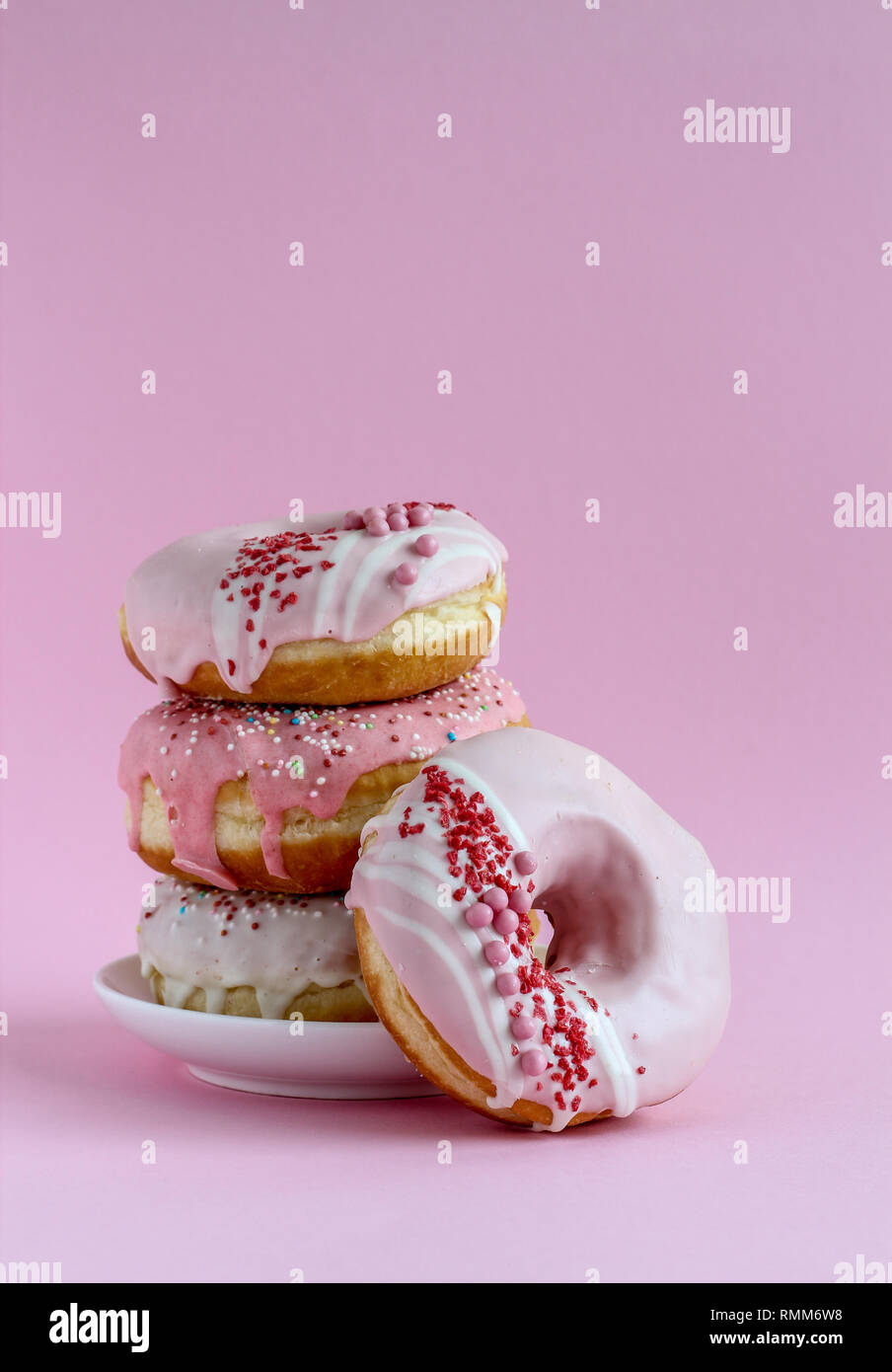 A stack of pink donuts on a pink background Stock Photo - Alamy