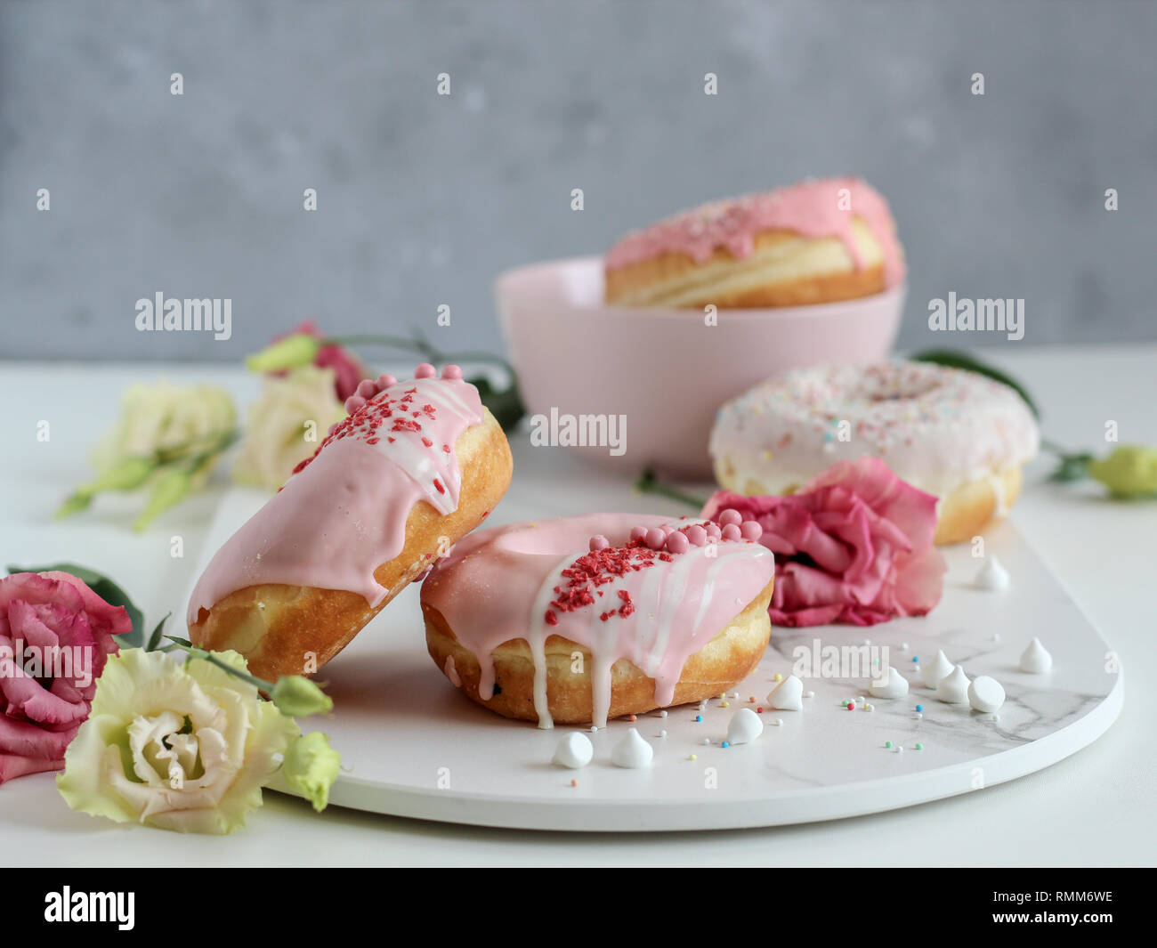 A stack of pink donuts with flowers on a dark background Stock Photo ...