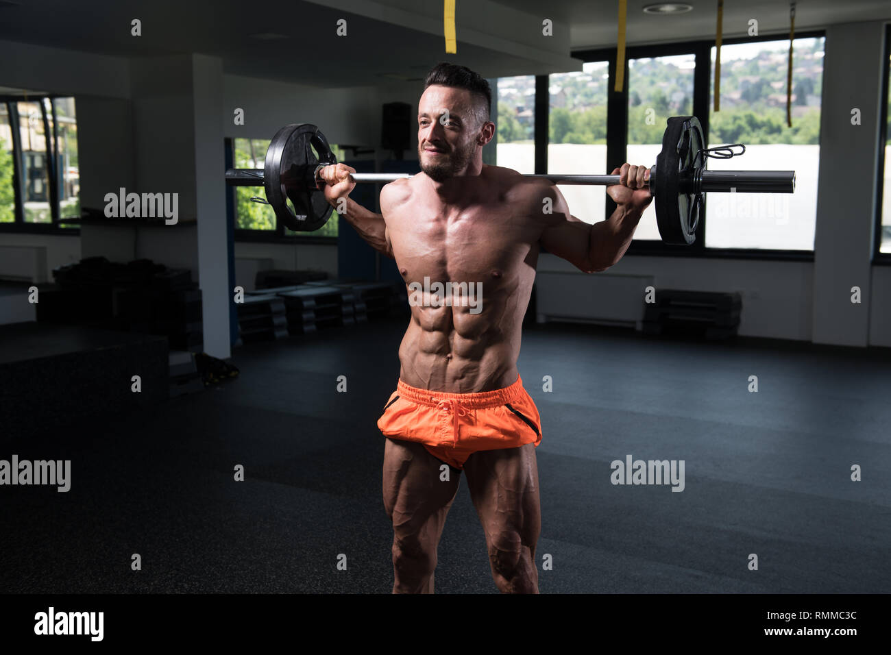 Strong Man In The Gym Exercising Quadriceps And Glutes With Barbell ...