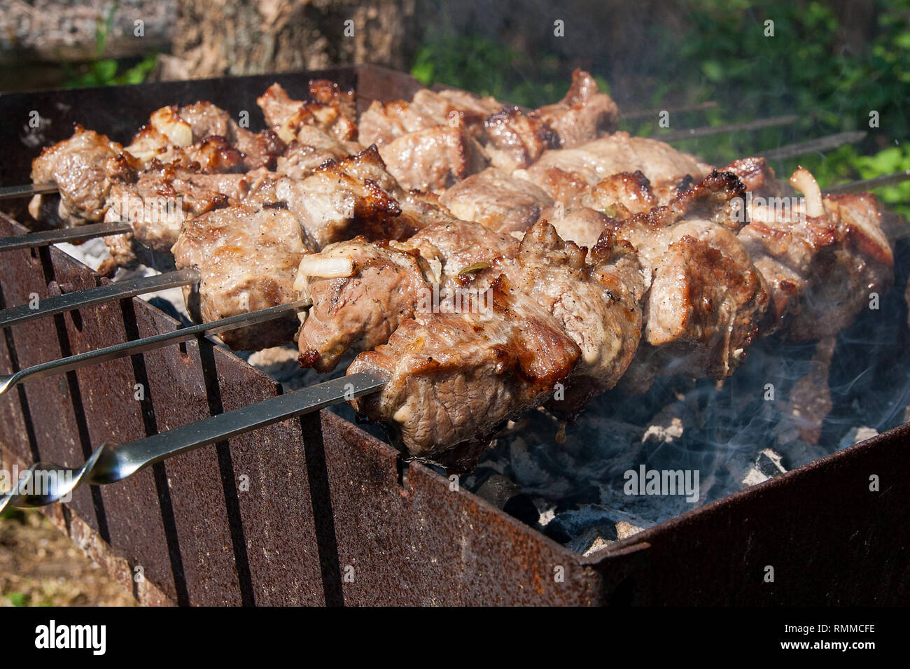 Grilled kebab cooking on metal skewer. Shashlik made of cubes of meat ...