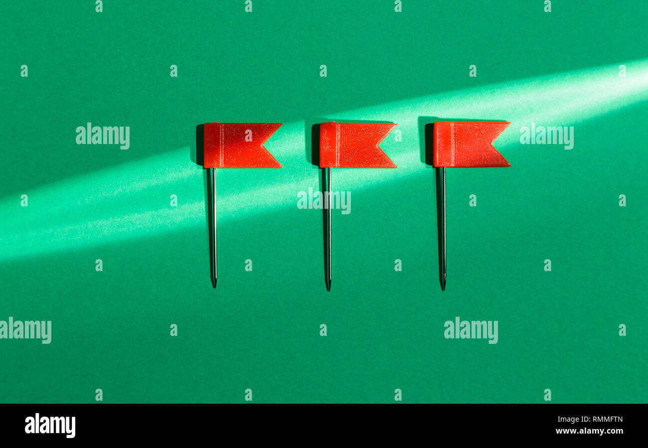 Three red little flag pins on a green background. View from above Stock ...