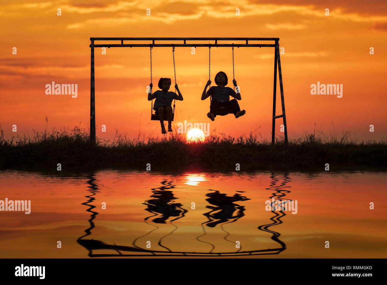 Silhouette of two girls swinging on swings at sunset, Thailand Stock ...