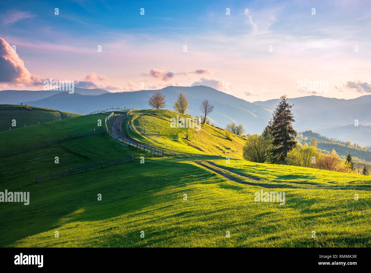 beautiful countryside in mountains at sunset. country road and fence ...