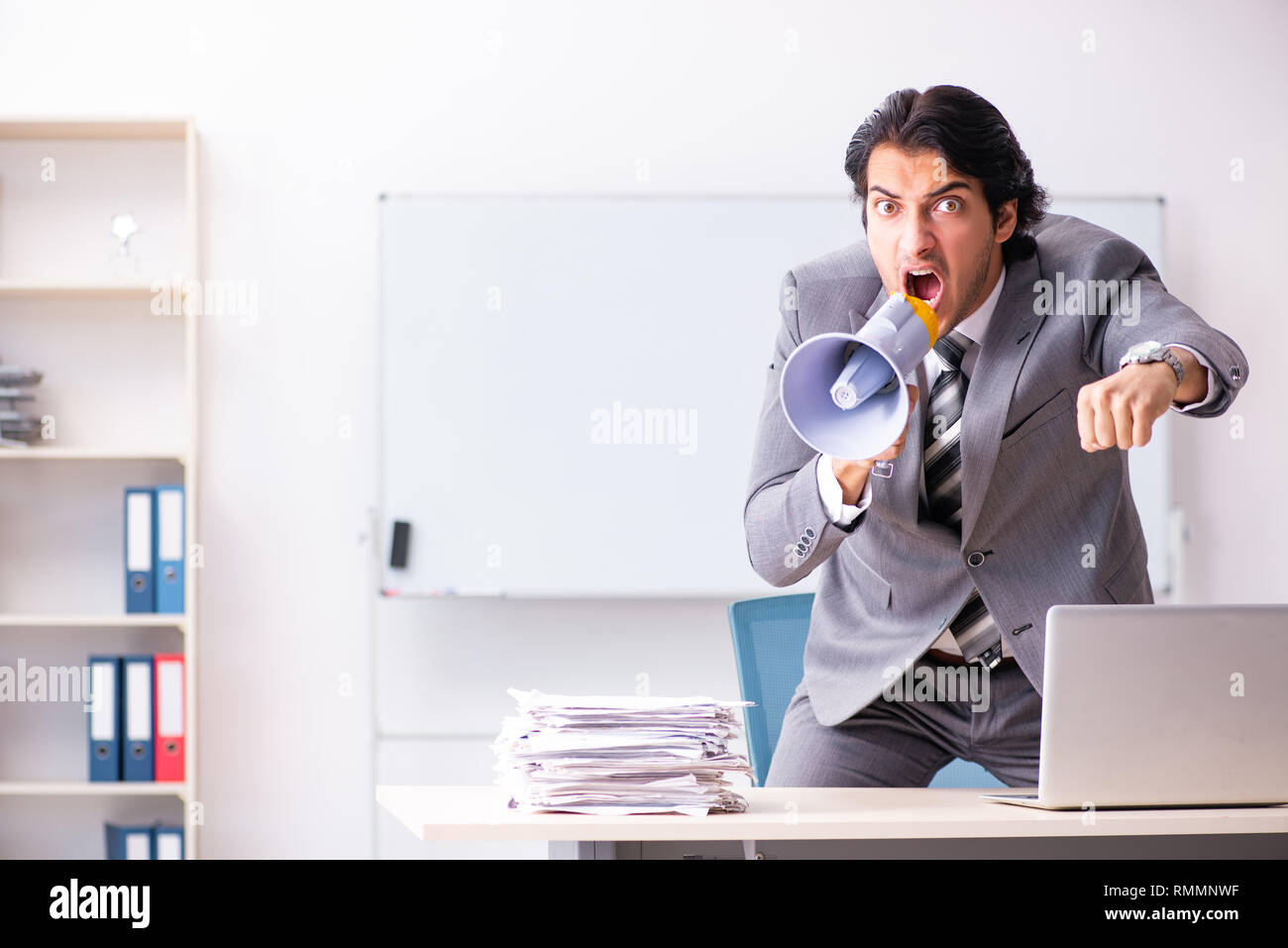 Young employee boss with megaphone in the office Stock Photo - Alamy