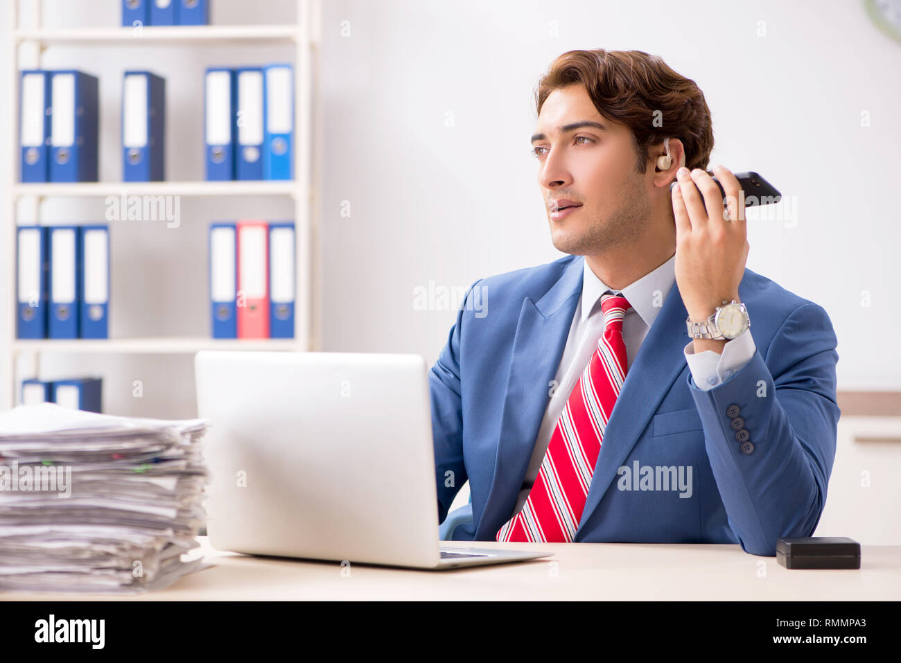Deaf employee using hearing aid in office Stock Photo - Alamy