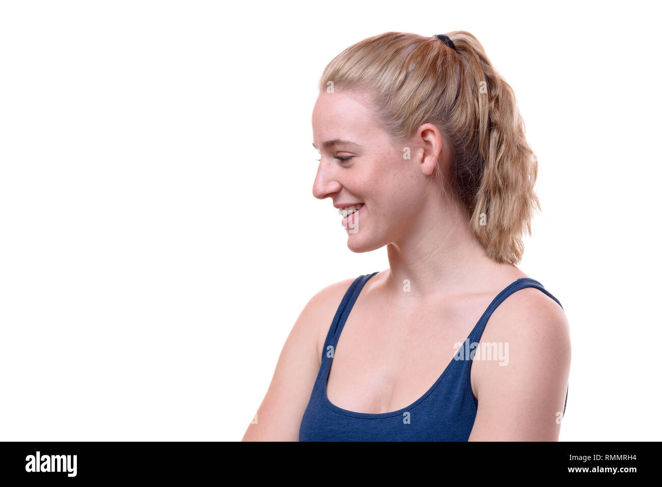 Smiling friendly young blond woman looking down to the side in a head ...