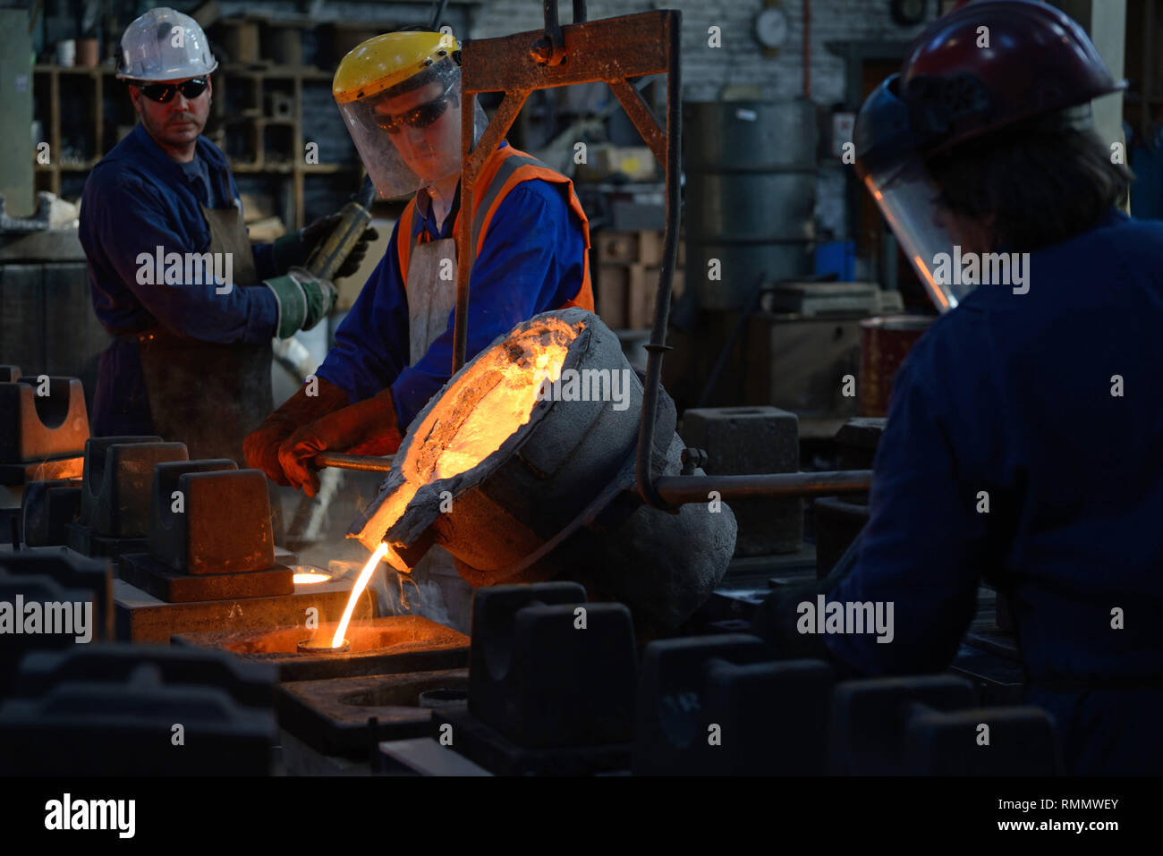 Foundrymen pour molten iron into moulds for making fire grates Stock ...