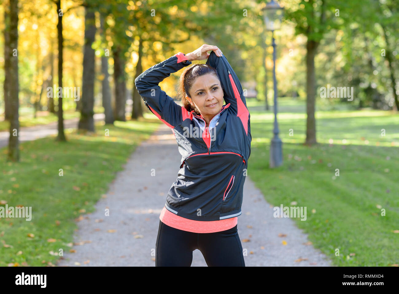 Adult woman wearing sportswear stretching in park on sunny day Stock ...