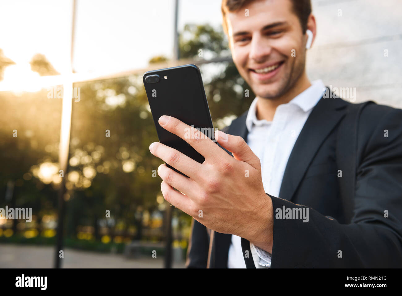 Photo of office worker in suit holding mobile phone while standing ...