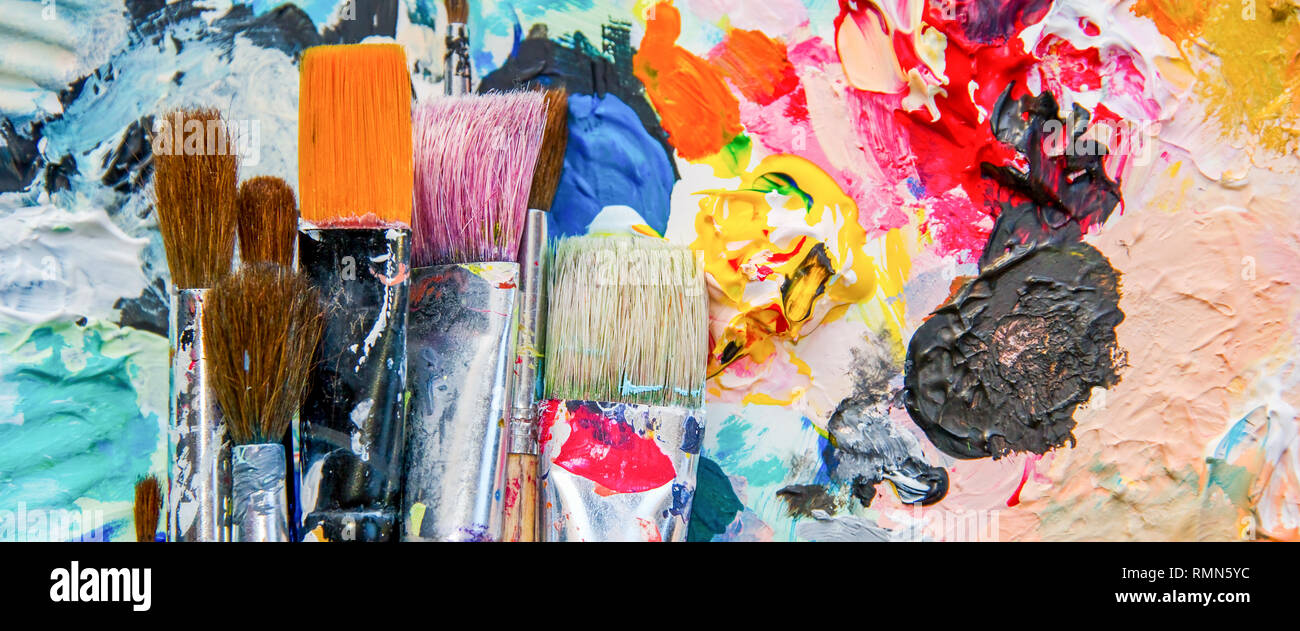 Used paint brushes on a colorful painter palette Stock Photo - Alamy