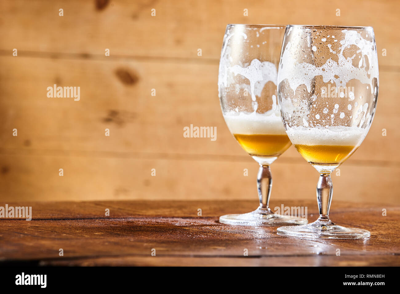 Two emptied glasses of beer on a counter with remnants of the lager and ...